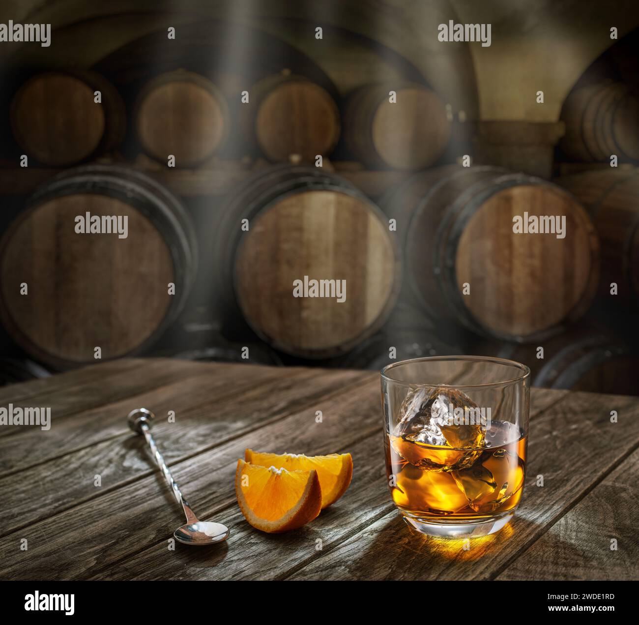 Glass of whiskey on top of wooden barrel and wood barrels in cellar at ...