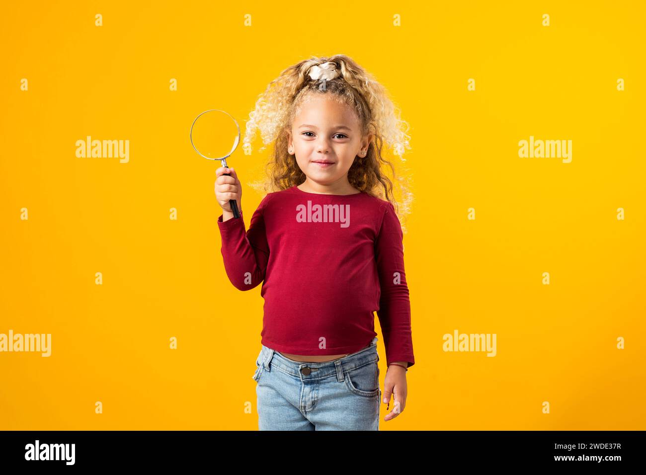Litle girl holding a magnifier in hand, exploring the world with ...