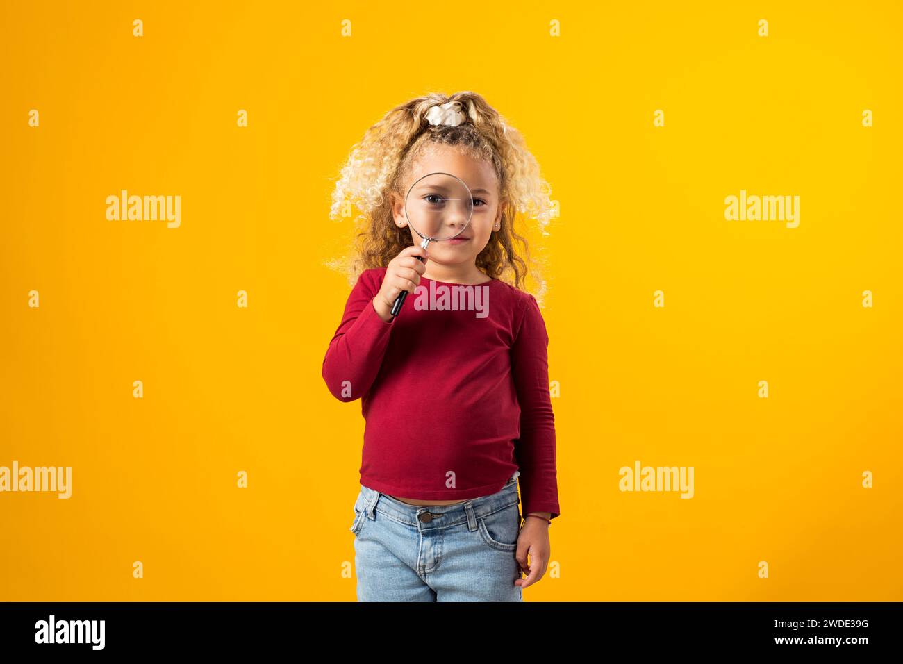 Litle girl holding a magnifier in hand, exploring the world with ...
