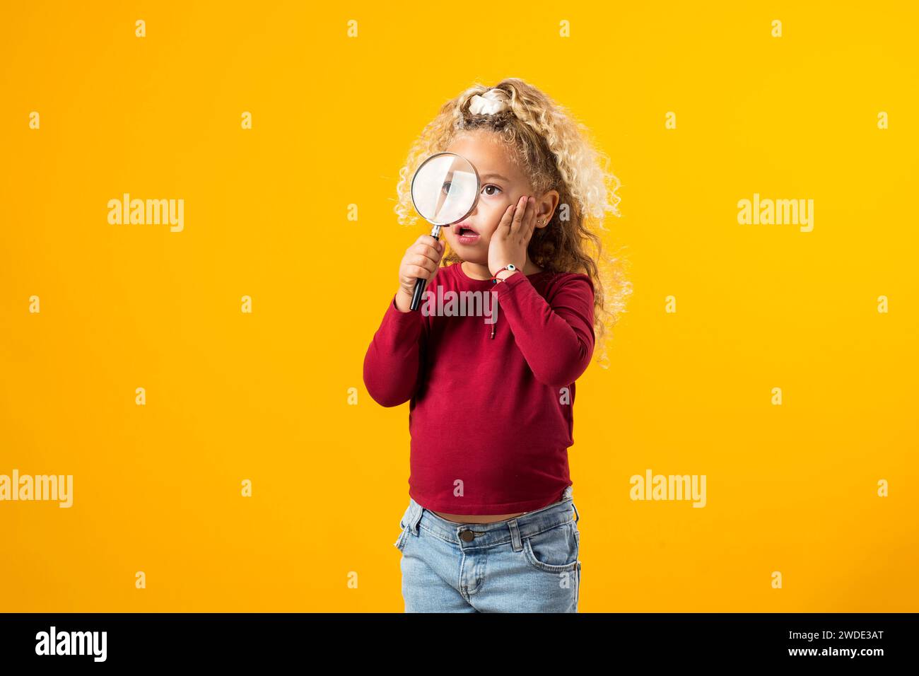 Litle girl holding a magnifier in hand, exploring the world with ...