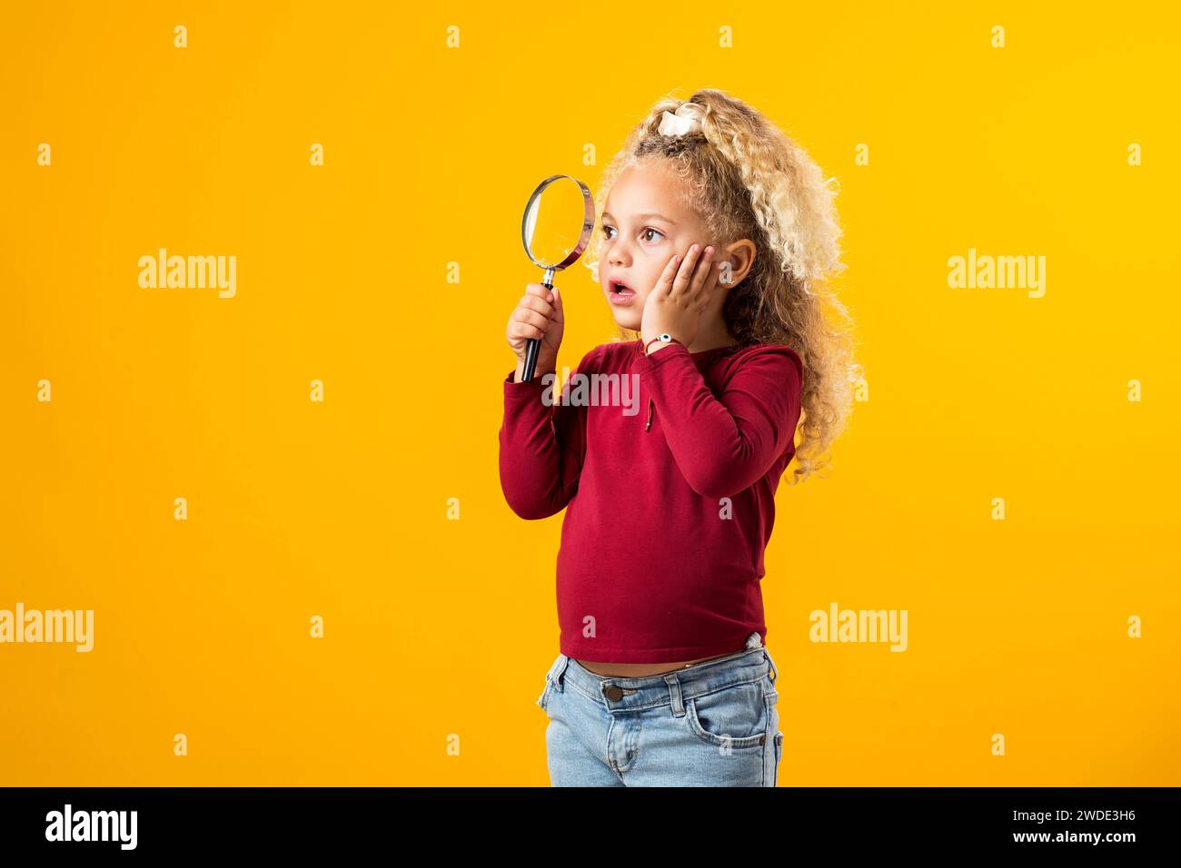 Litle girl holding a magnifier in hand, exploring the world with ...