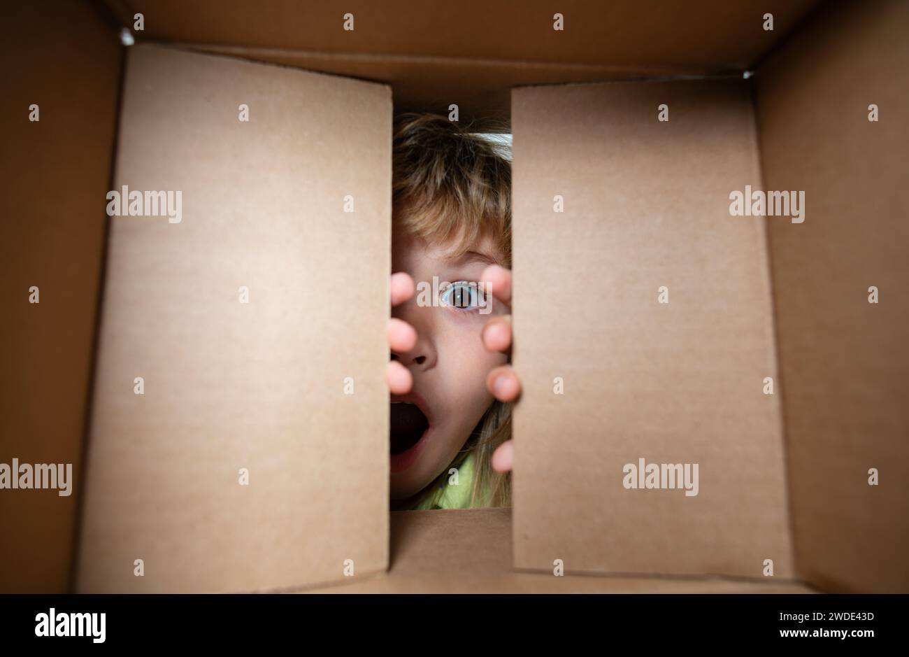 Child boy opening a carton box and looking inside, unpacking concept ...