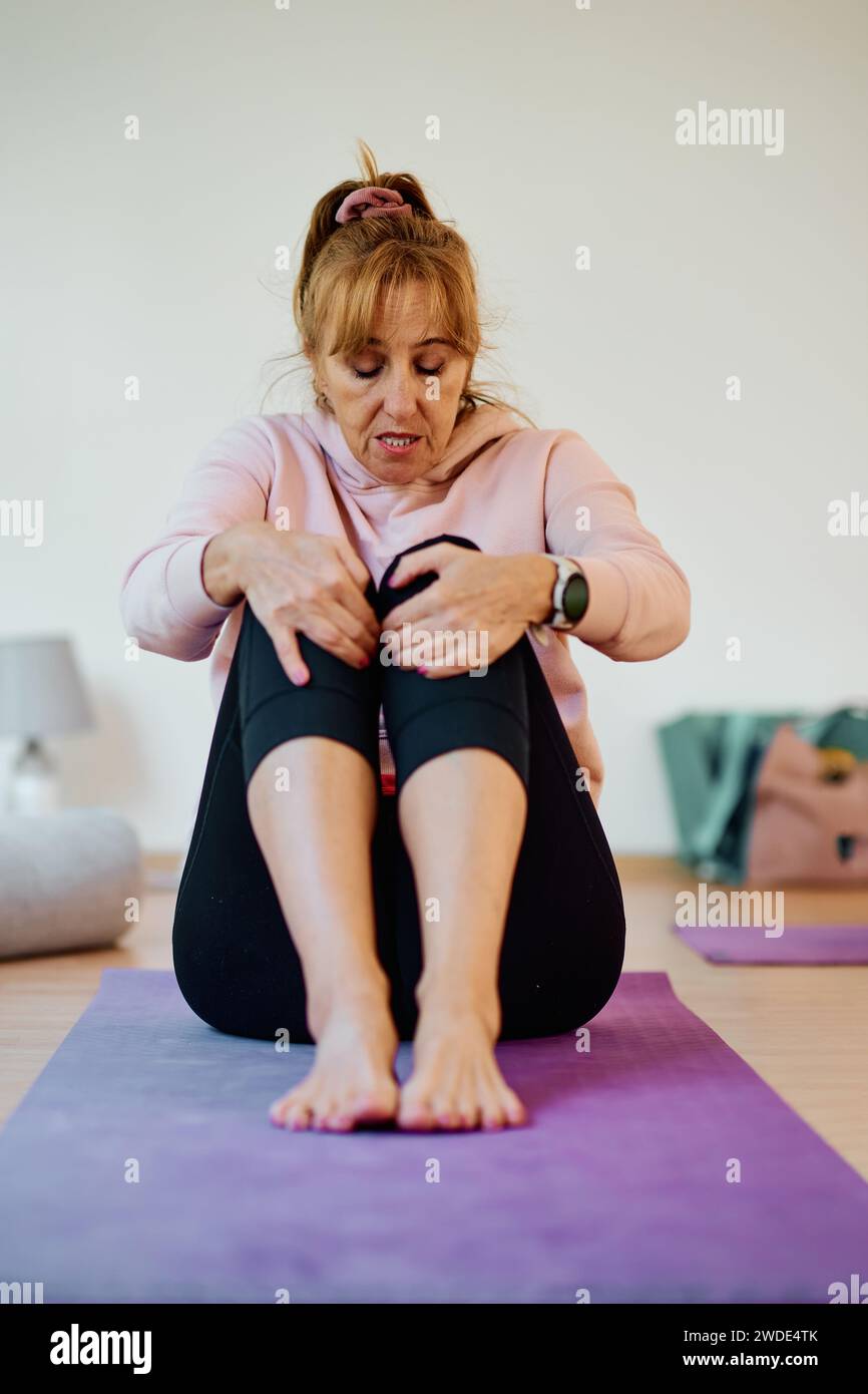 In a sunlit space, a senior woman gracefully practices rejuvenating ...