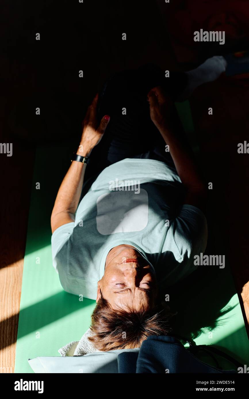 In a sunlit space, a senior woman gracefully practices rejuvenating ...