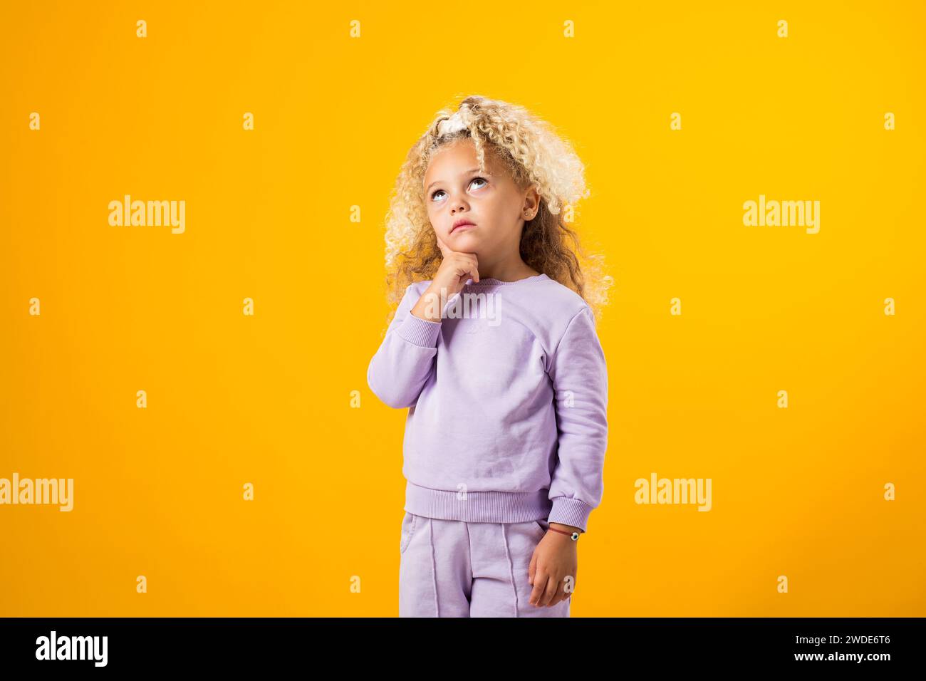 Portrait of thoughtful child girl touching chin with finger thinking or ...