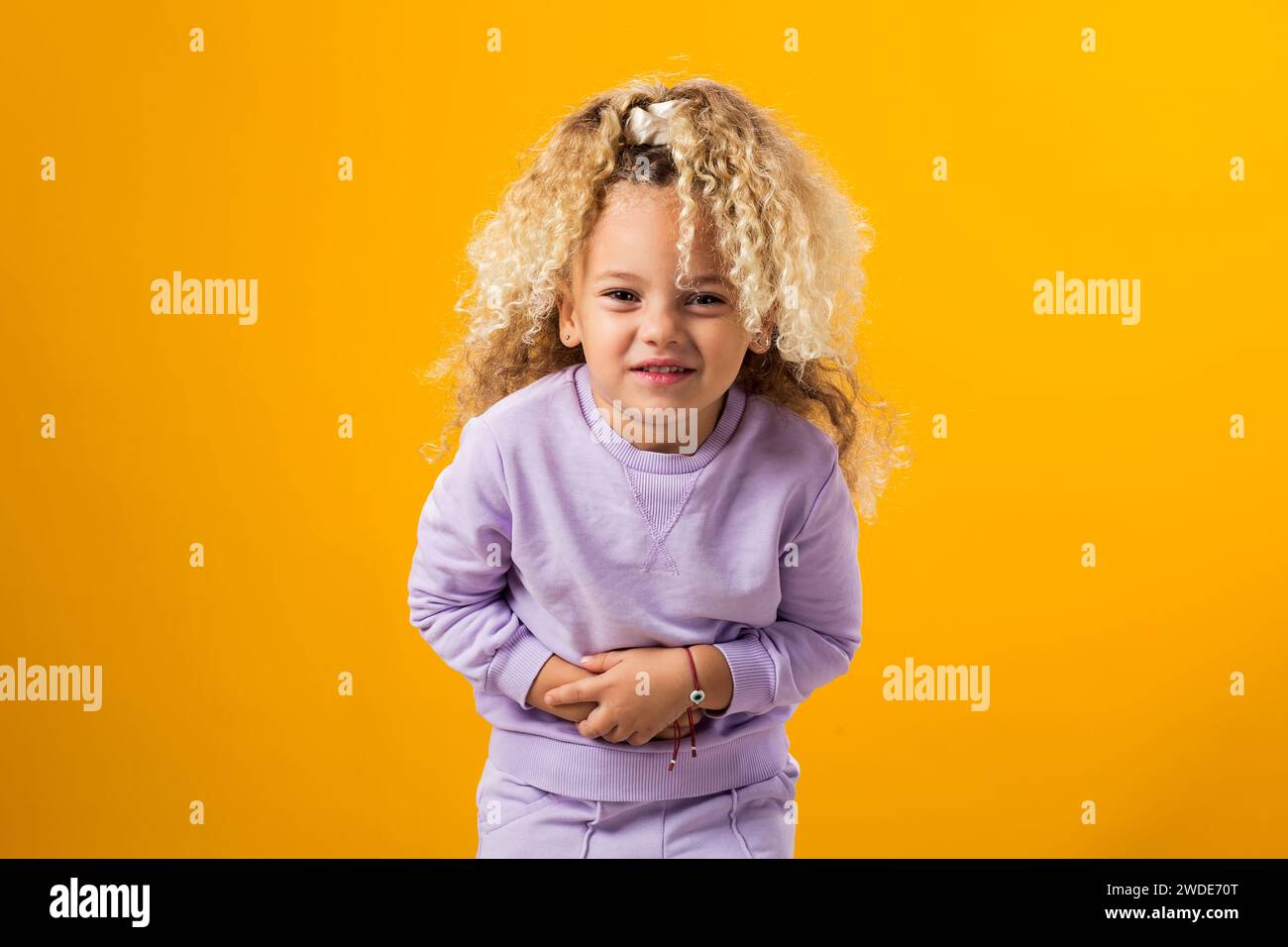 Portrait of child girl feeling abdominal pain, keeping hands on stomach ...