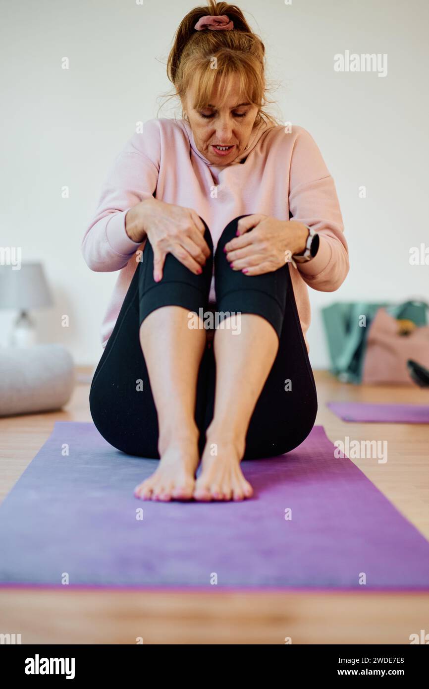 In a sunlit space, a senior woman gracefully practices rejuvenating ...
