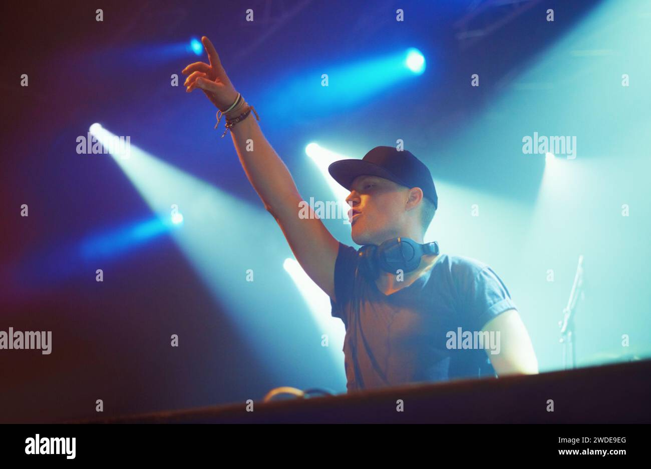 Man, headphones and stage lighting for music performance or techno ...