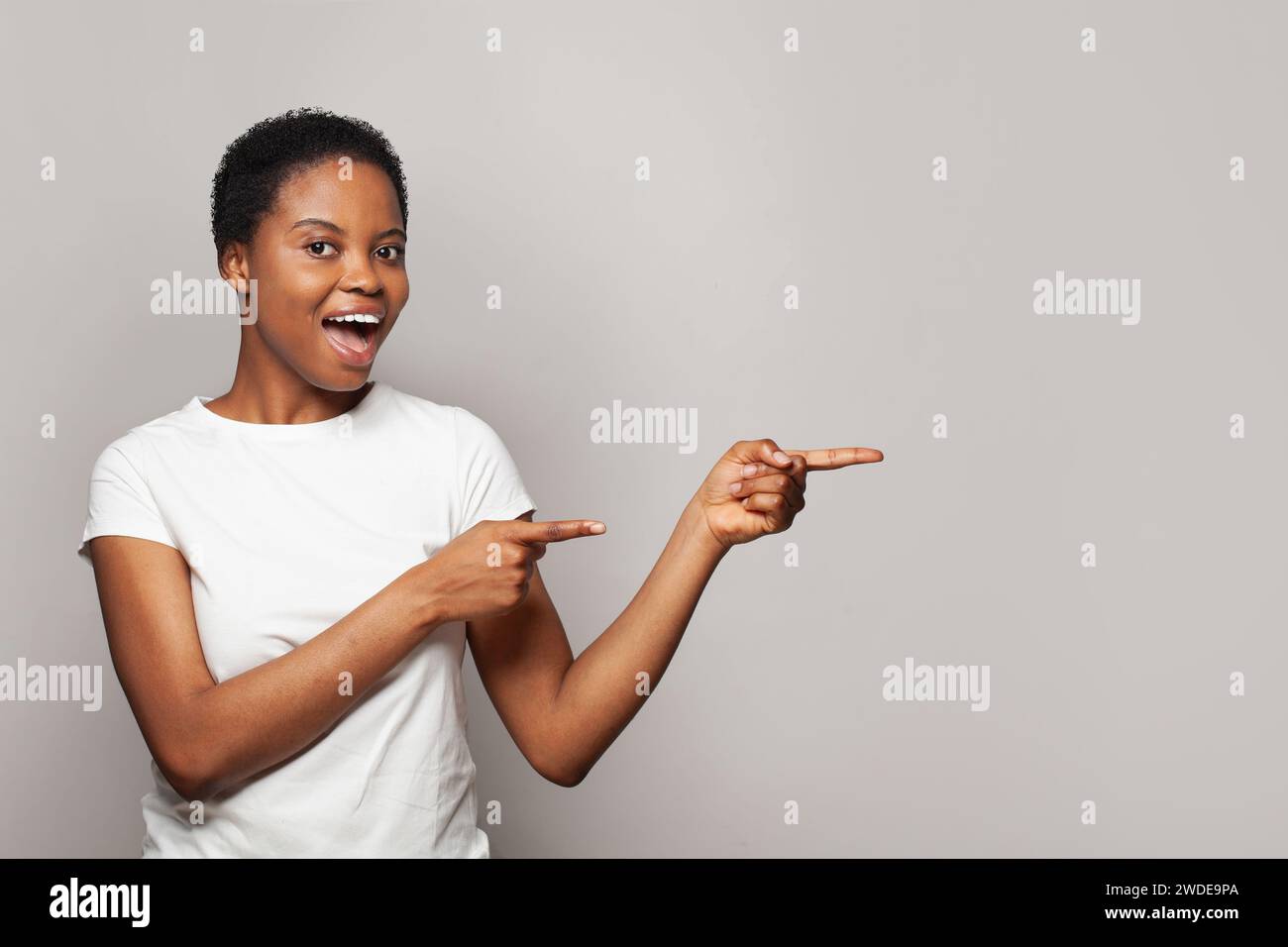 Beautiful woman pointing finger at light gray studio wall banner ...
