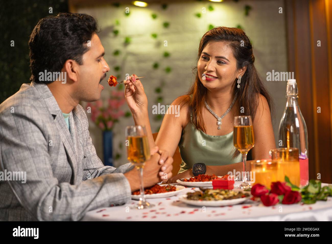 Romantic woman feeding his husband by giving bite during candlelight ...