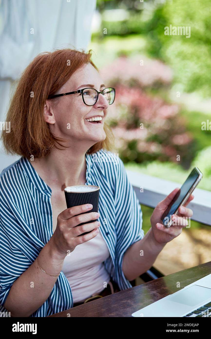 Digital life - cheerful woman browsing on her phone with a drink Stock ...