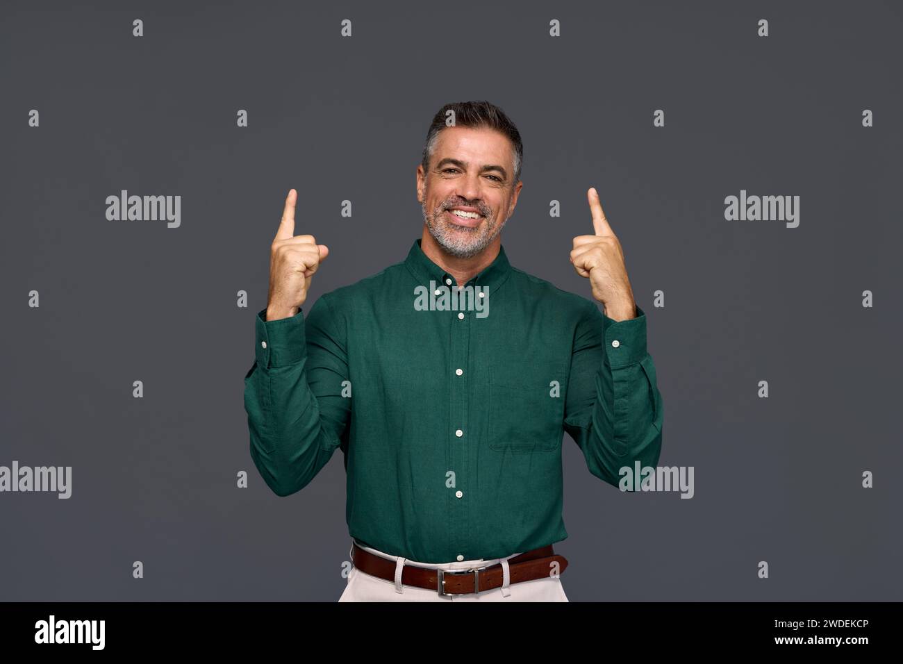 Happy middle aged business man pointing up advertising isolated on gray ...