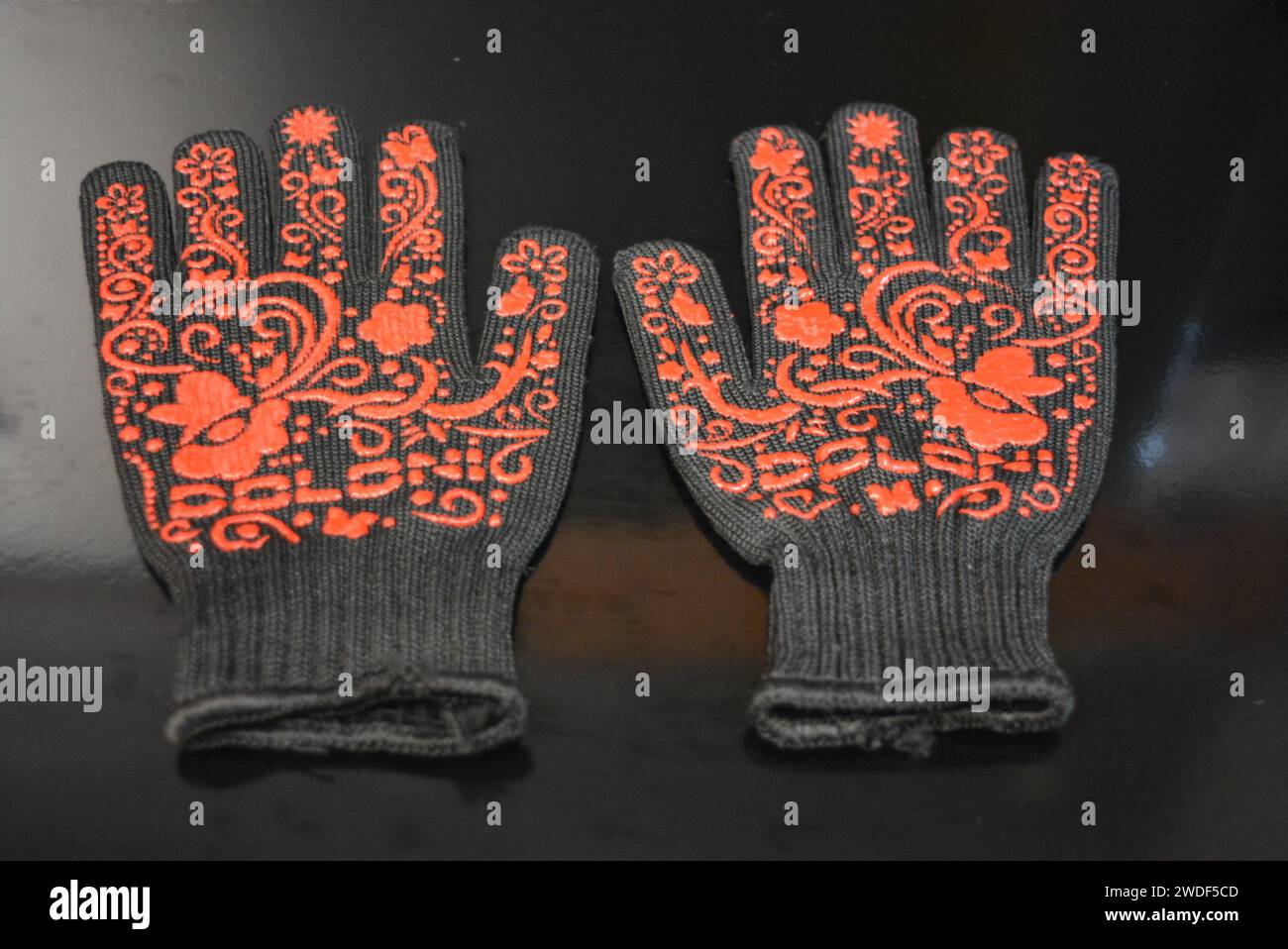 On a black glossy background, workers are treated black female gloves ...