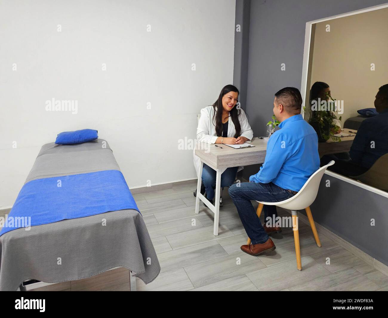 Latin female doctor attends to a dark-skinned male patient in her ...