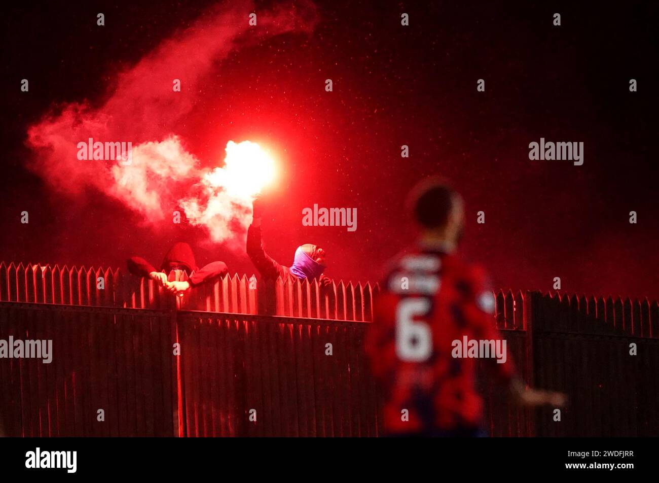 A fan lets off a smoke flare as they watch the match action from over a ...