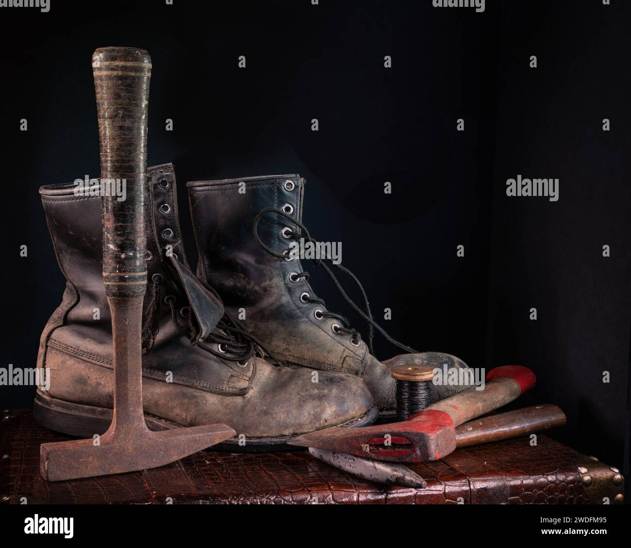 Old leather work boots and pick axe on a suitcase still life Stock ...