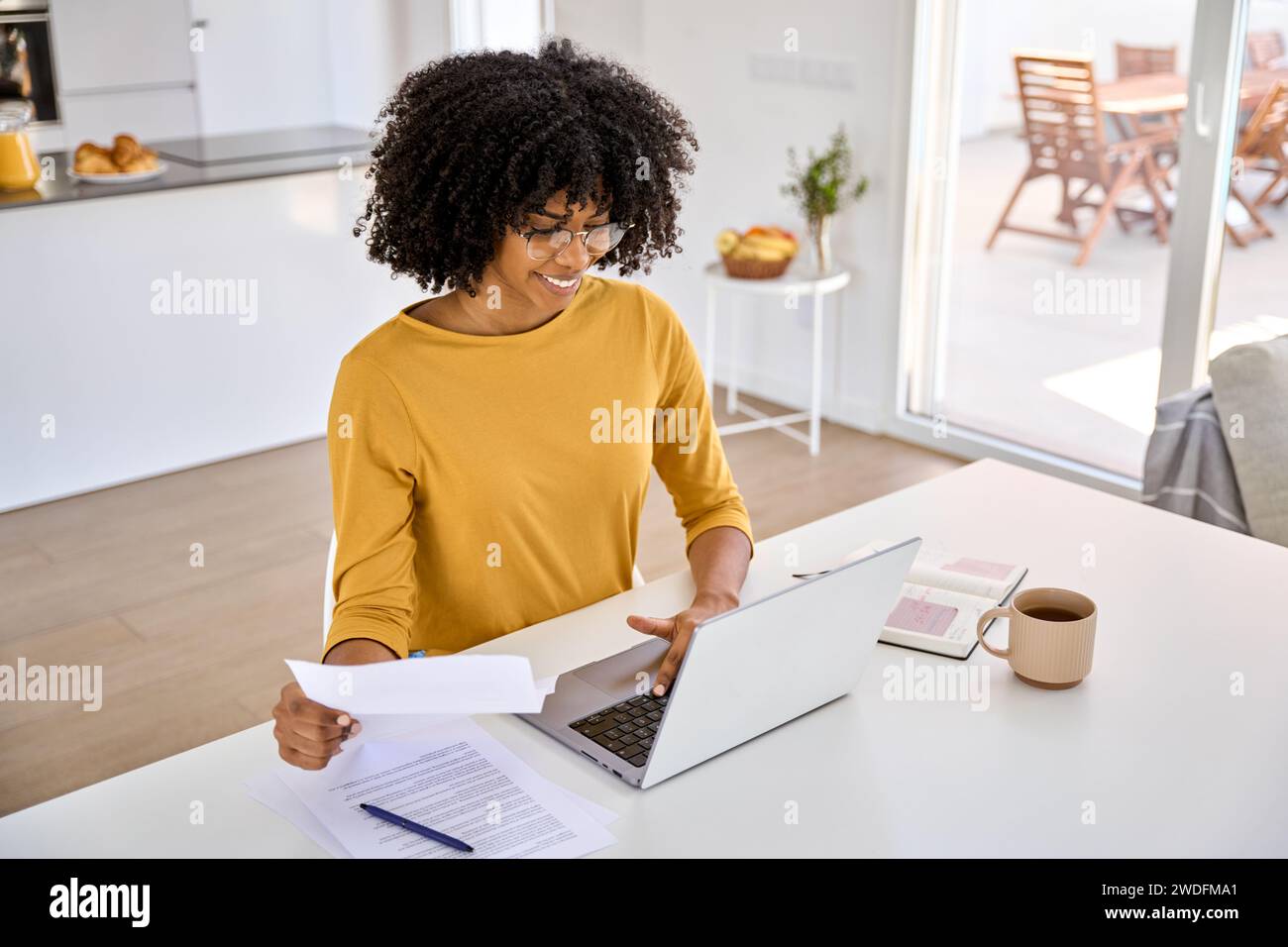 Young smiling happy African woman checking paper paying bills online at ...