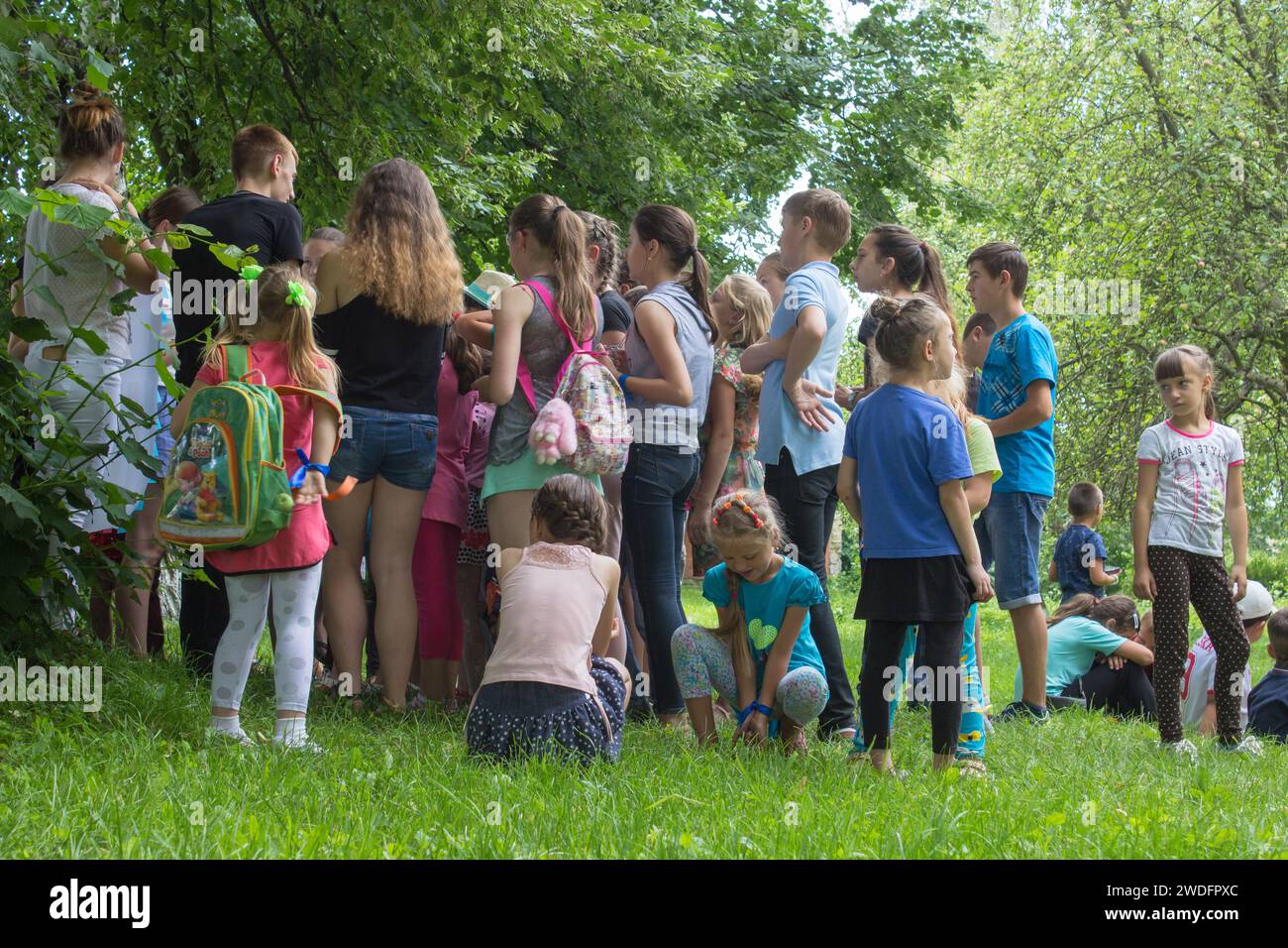 children are standing in a pile in the nature and listen to the teacher ...