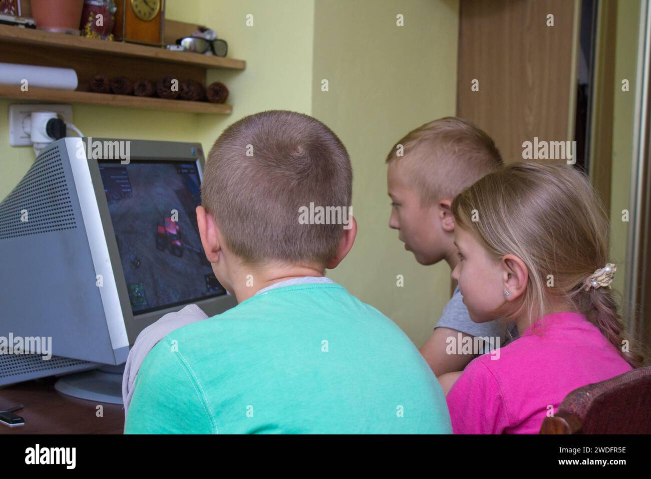 three children sitting behind an old computer Stock Photo - Alamy