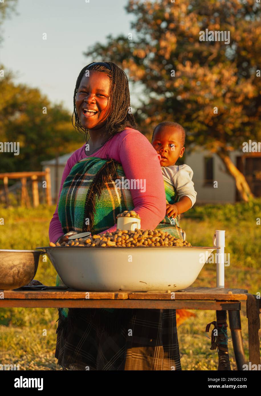 village street vendor, african woman with baby carry in the back ...