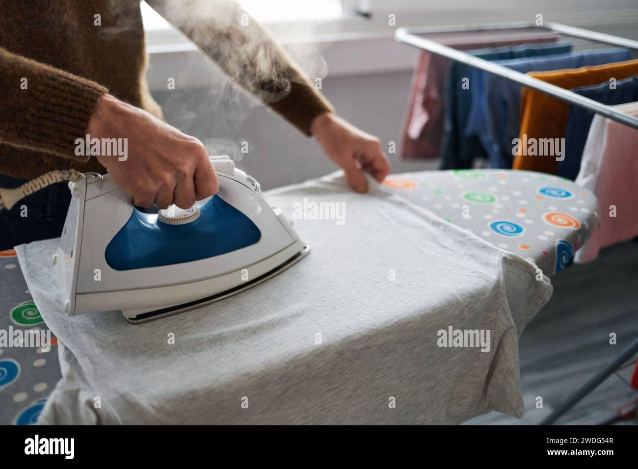 Hands of a mature man ironing laundry with steaming. Close-up. Clothes ...