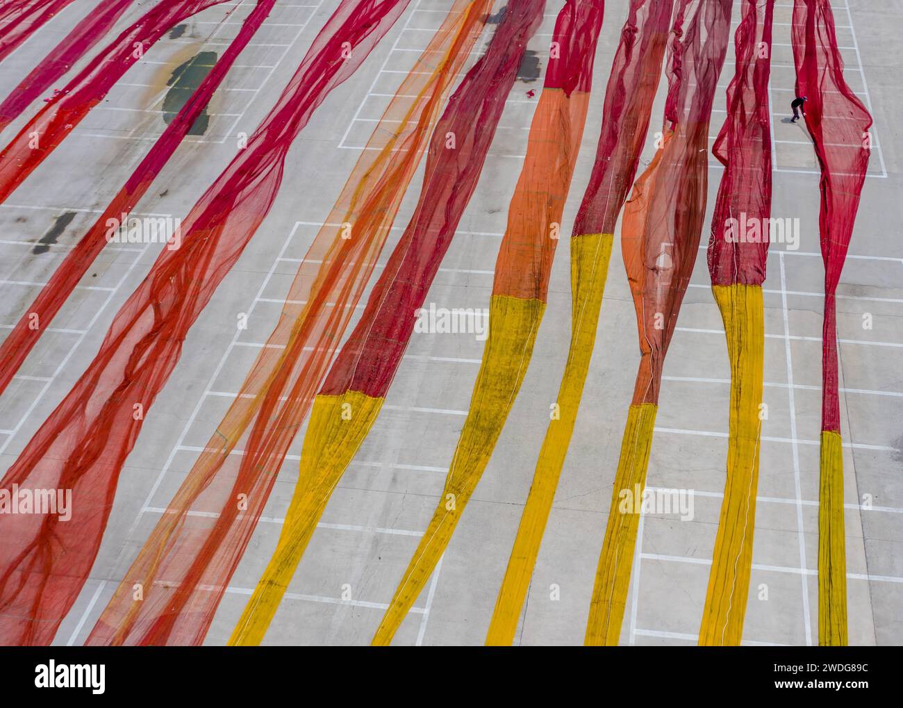 Aerial view of fishing nets in reds, oranges and yellows stretched out ...