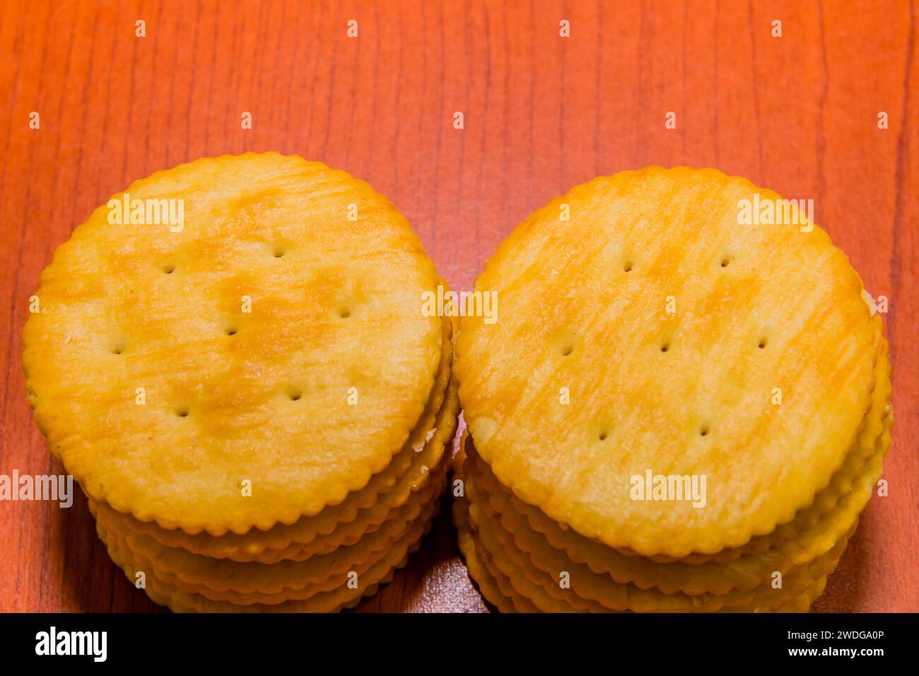 Closeup of two stacks of round butter crackers on brown wood grain ...