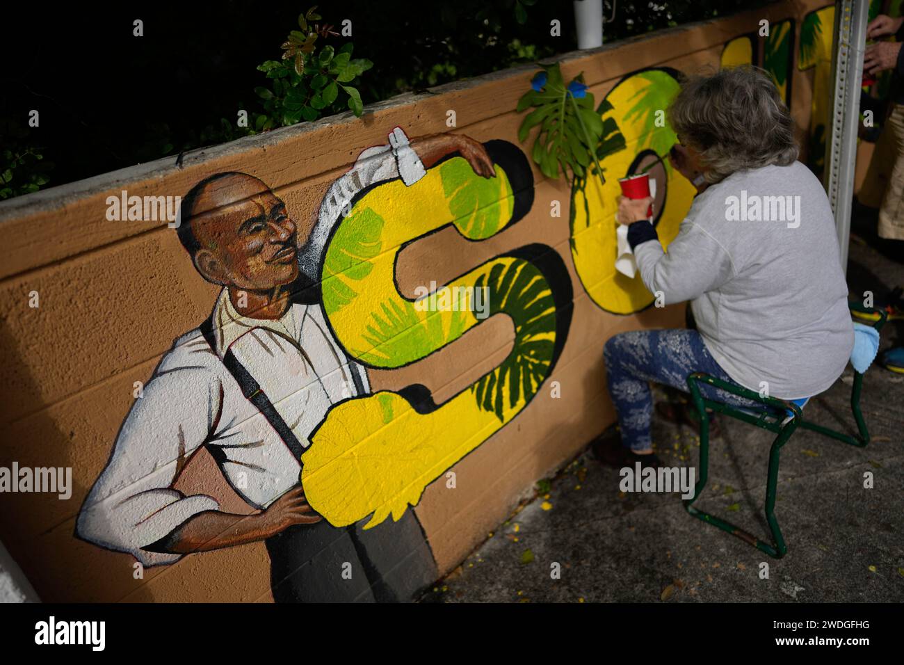 A volunteer paints details near an image of Marshall Williamson ...