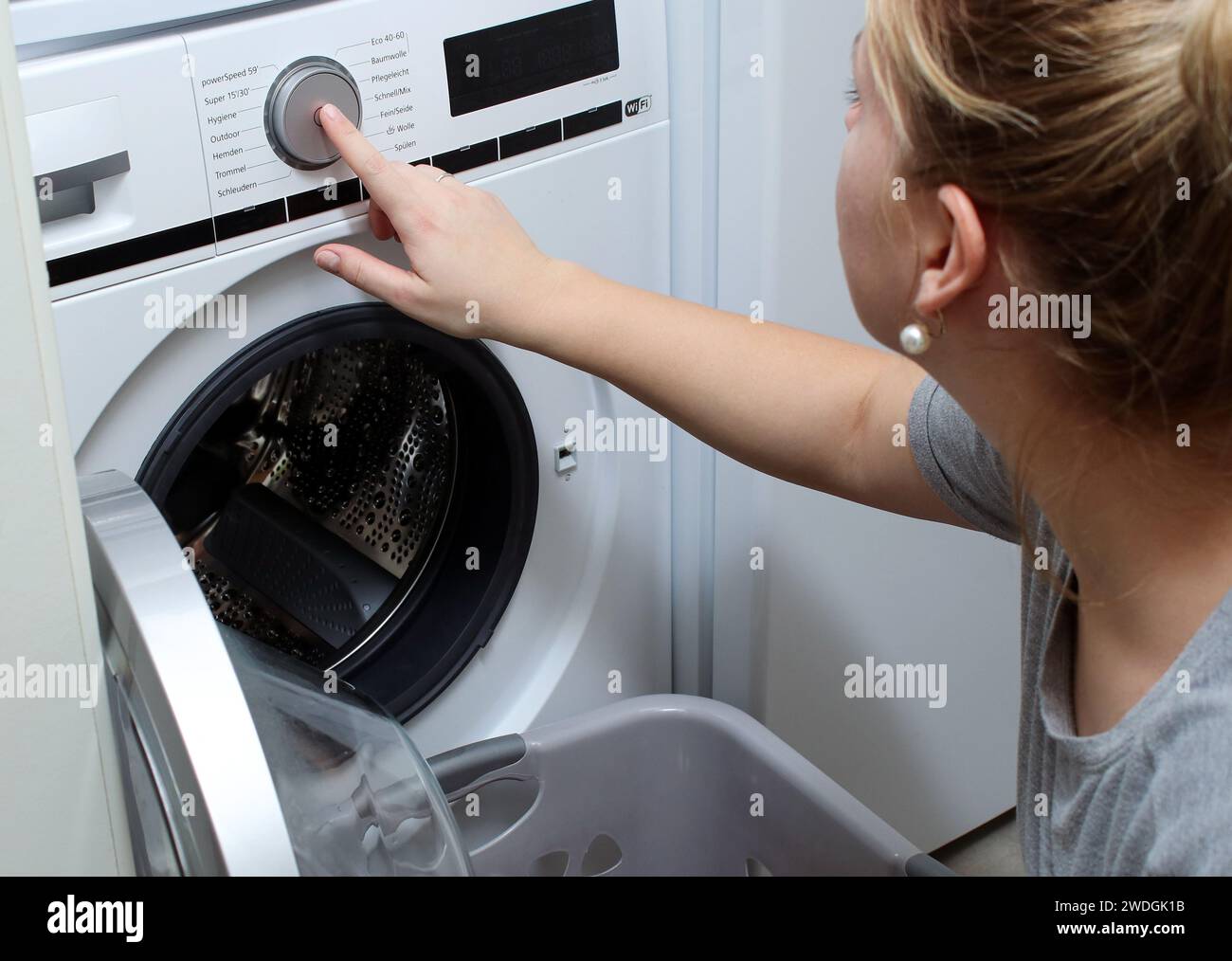 Close up of a caucasian woman pressing start button of a washing ...