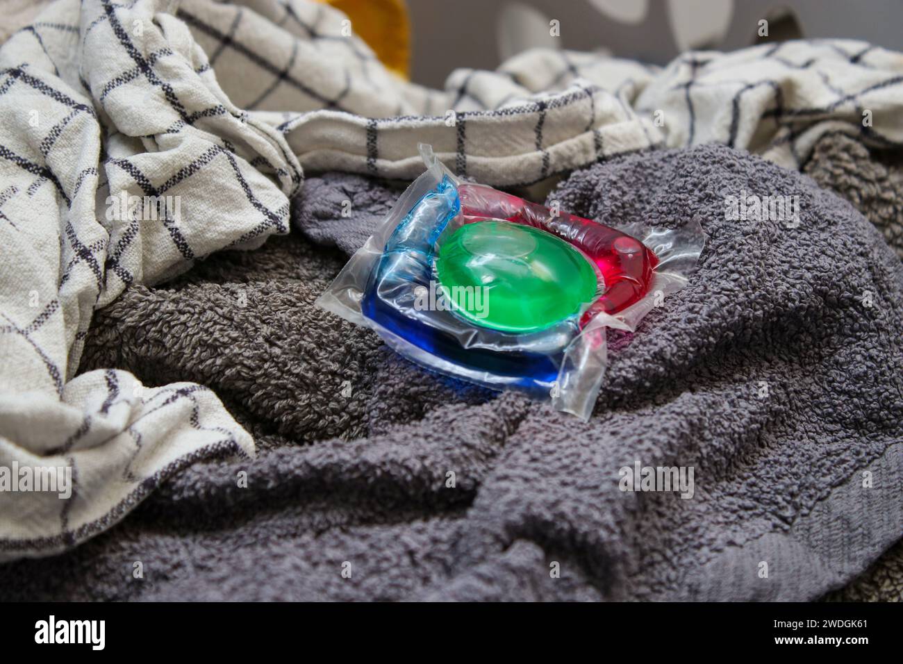 Close up of a colorful eco washing gel in capsule on laundry clothes ...