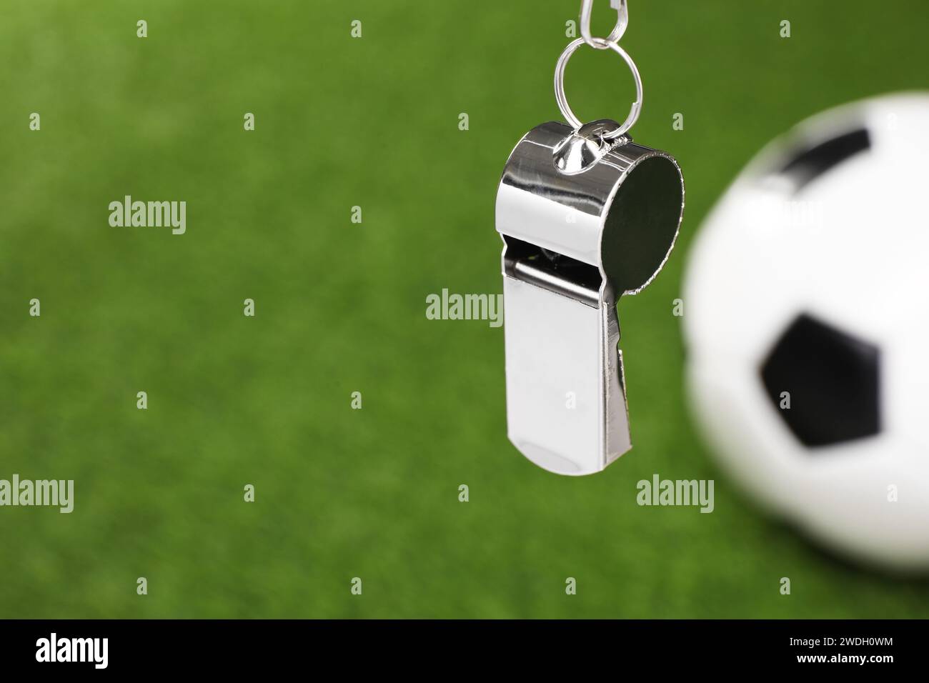 Football referee equipment. Metal whistle and soccer ball on green ...