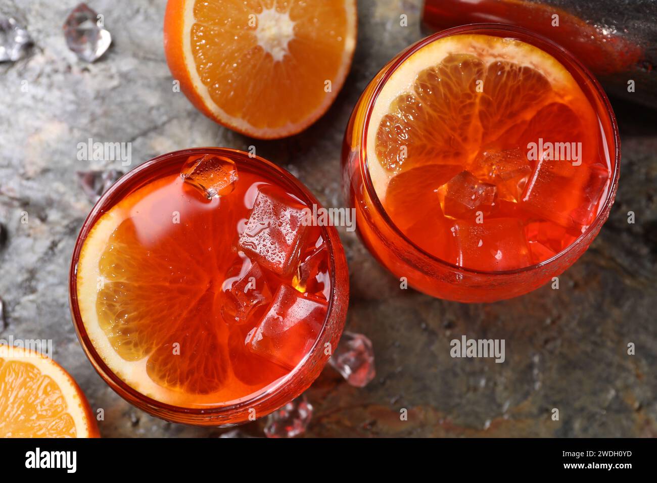 Aperol spritz cocktail, ice cubes and orange slices in glasses on grey ...