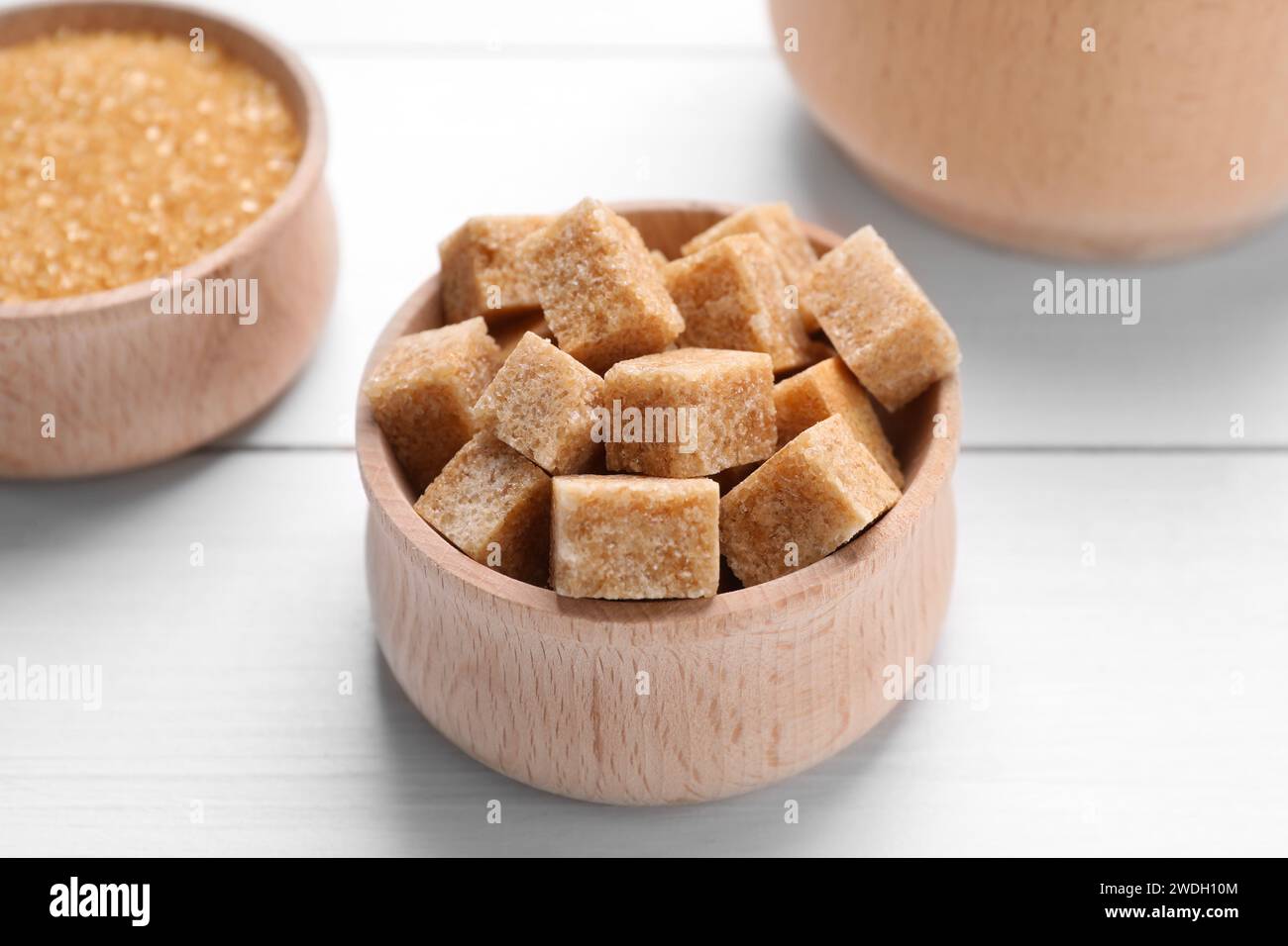 Different types of brown sugar in bowls on white wooden table, closeup ...