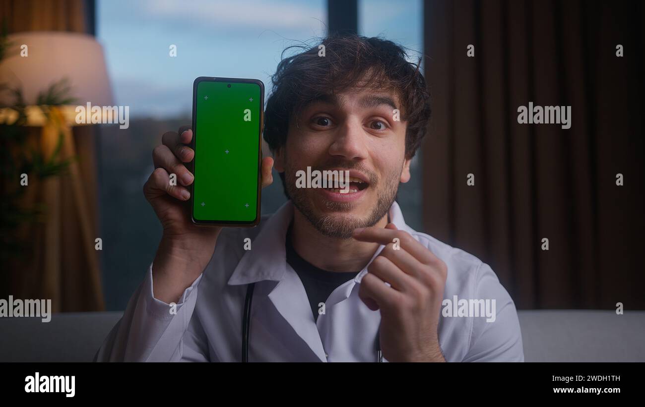 Smiling male doctor wear uniform with stethoscope show app on the phone ...