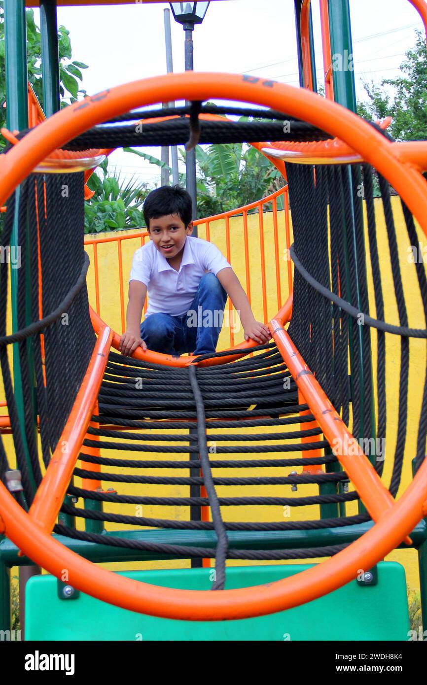 9-year-old dark-skinned Latino boy plays in a playground as a physical ...