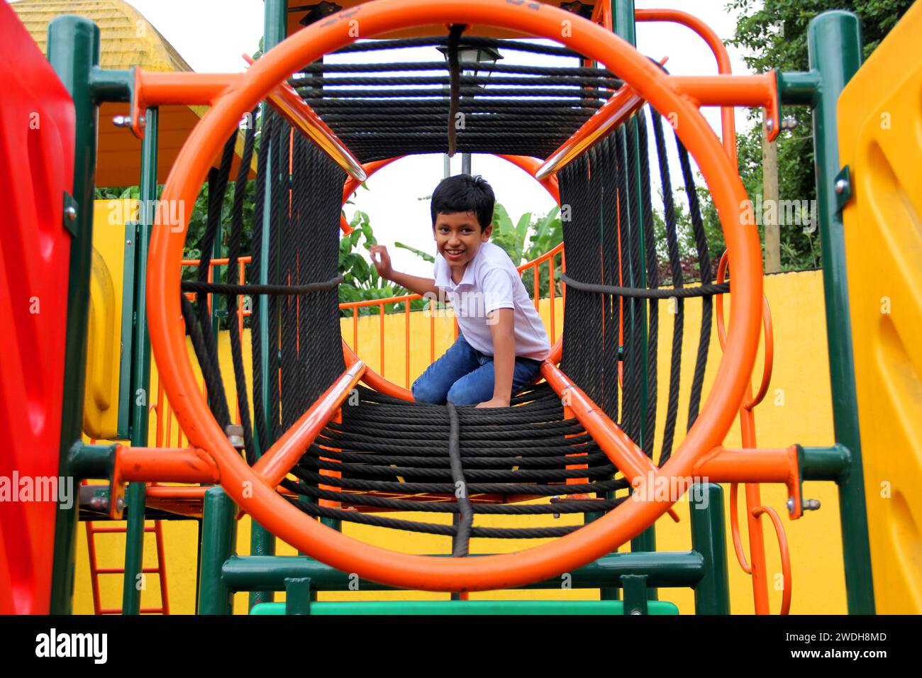 9-year-old dark-skinned Latino boy plays in a playground as a physical ...