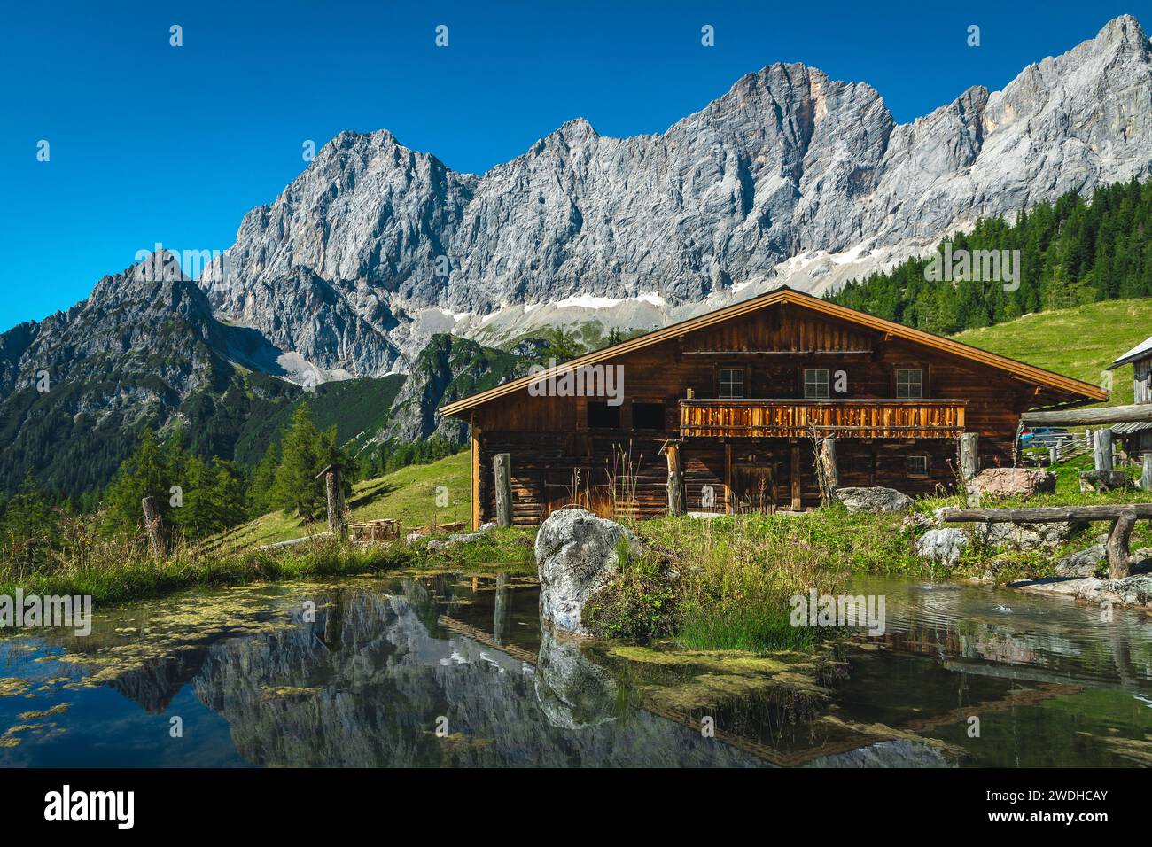Majestic alpine scenery, cozy wooden log house on the small lake shore ...