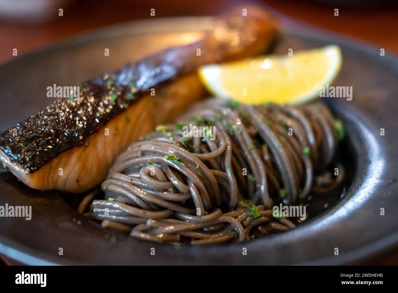 Cold soba noodle with pan seared salmon served on plate with lemon ...