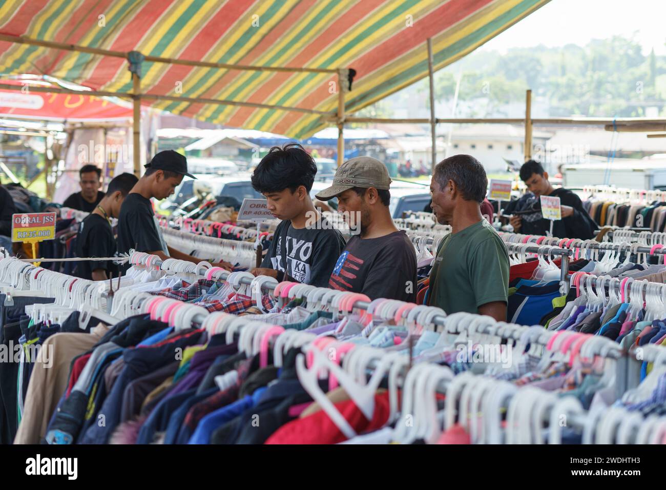 Residents selecting and buying secondhand clothes in a thrift shop at Pasar Pon traditional ...