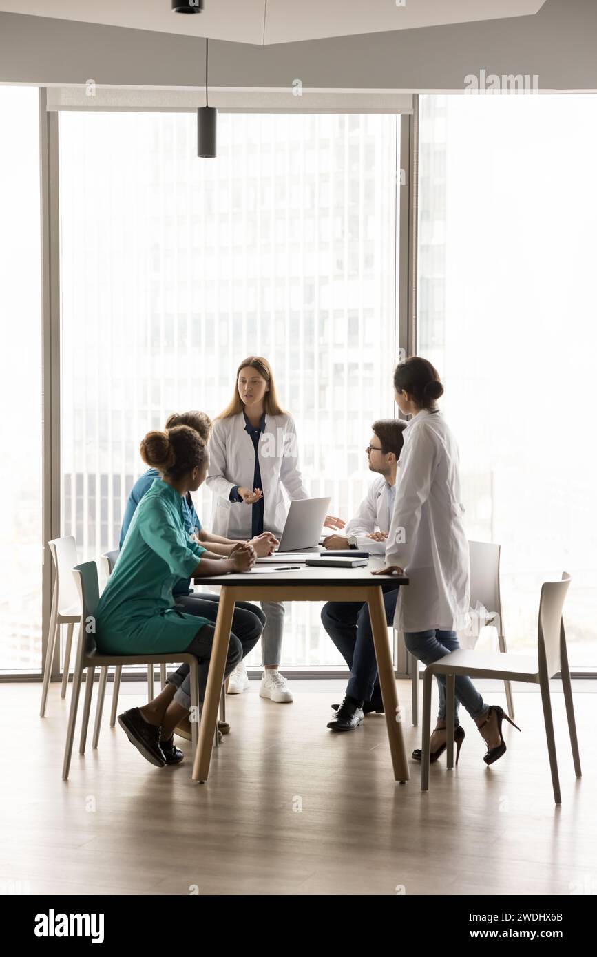 Young female chief doctor holding meeting with diverse medical team ...