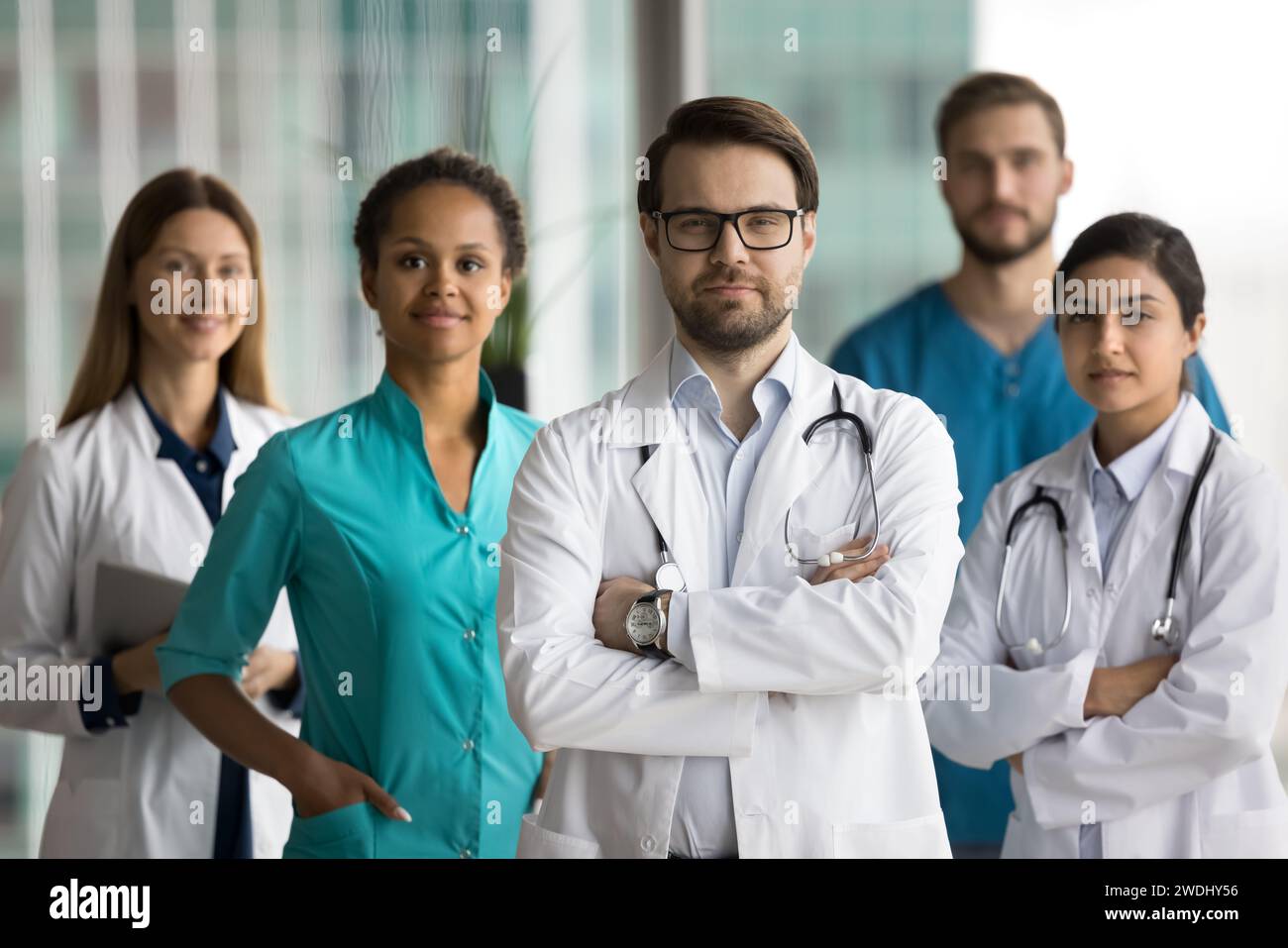Confident head doctor standing in front of diverse team Stock Photo - Alamy