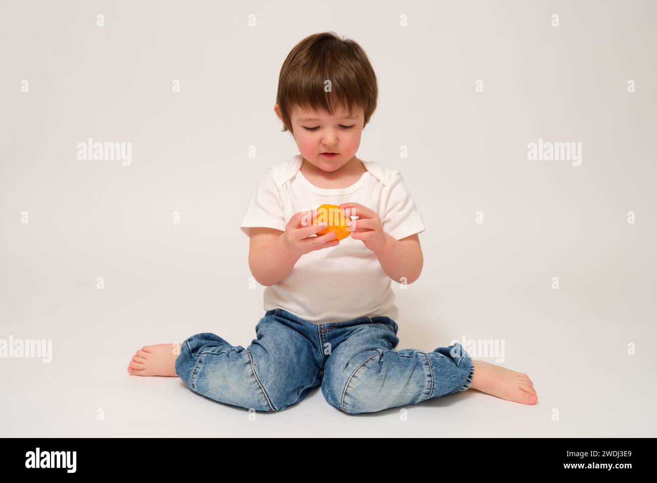 Toddler baby is playing with plasticine, studio white background. A ...