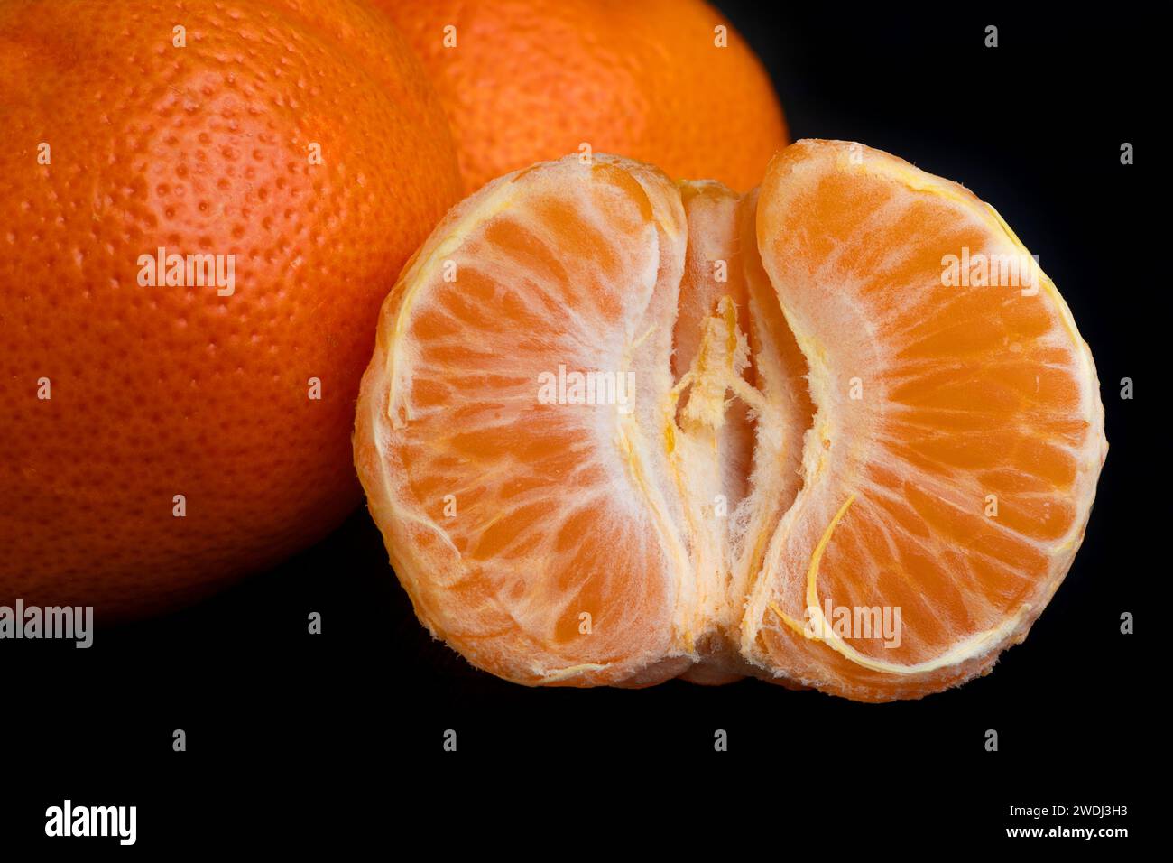 Half of a peeled tangerine against the background of other whole ...