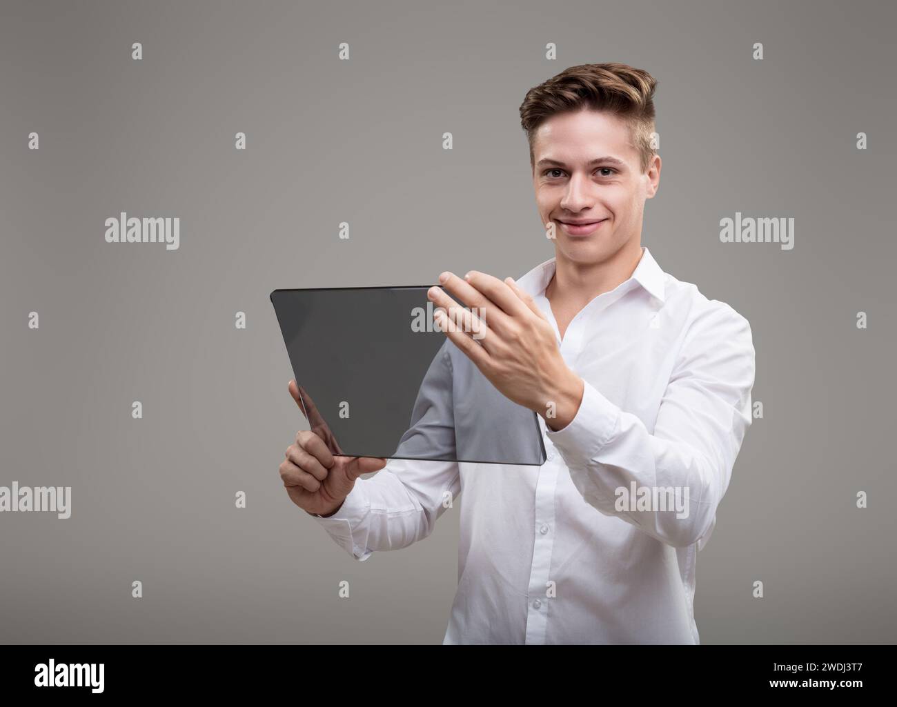 Smiling young visionary presents an ultrafuturistic transparent tablet ...