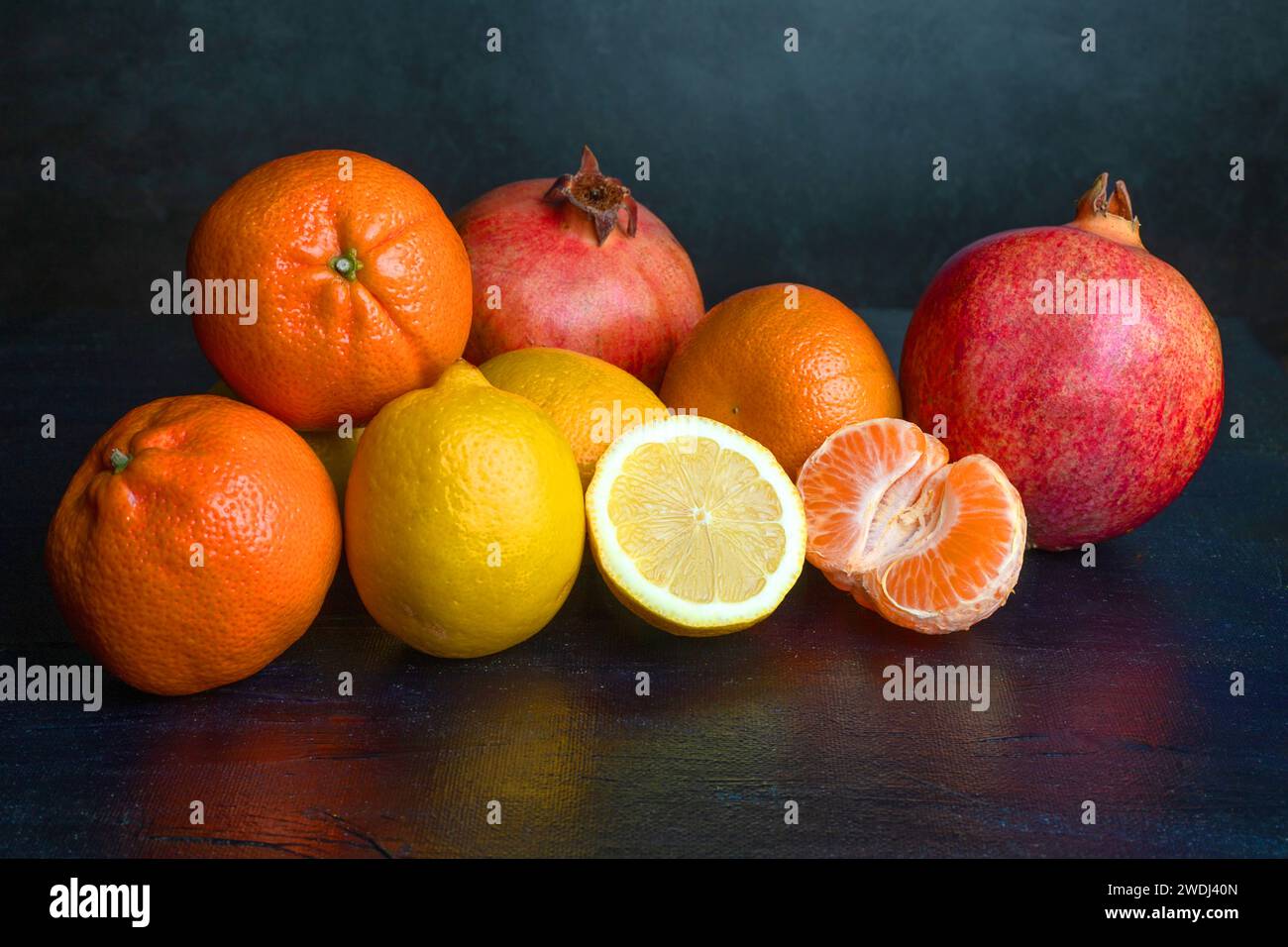 Tangerines, lemon, and pomegranate on a dark, graphite, black ...