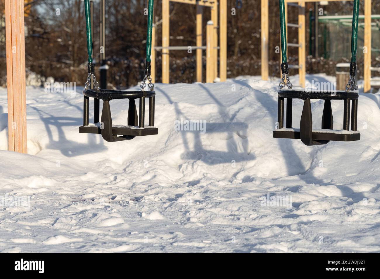 empty children's swings on a snowy playground. children's playground in ...