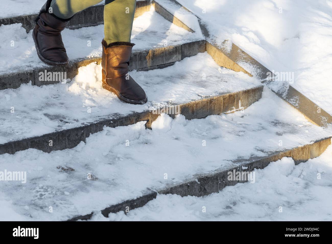 a man in winter shoes goes down the snow-covered steps. woman going ...