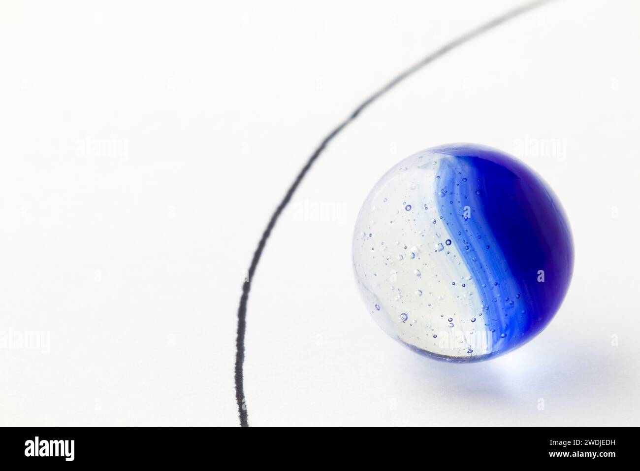 A blue glass marble inside a drawn circle Stock Photo - Alamy