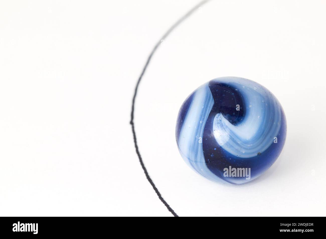 A blue glass marble inside a drawn circle Stock Photo - Alamy