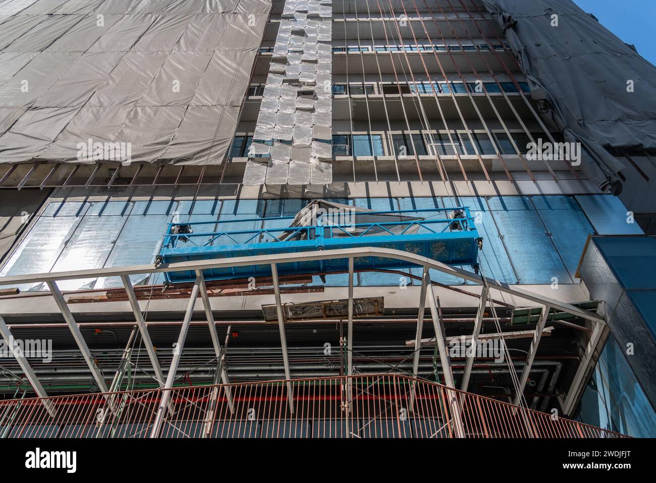 Construction blue concrete cradle on the lower floors of a skyscraper ...
